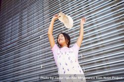Smiling Female In Floral Overalls With Hands And Cap Above Her Head ...