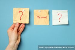 Person Reaching For Post It Notes With Question Mark On Blue Board ...