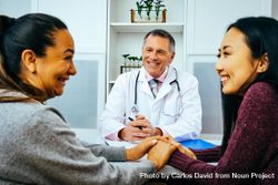Happy doctor sharing news with two smiling patients in medical office ...