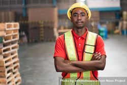 Man in PPE gear standing in distribution center with arms crossed ...