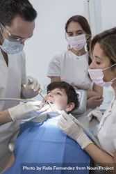 A portrait of dental team team working on young patient, vertical ...