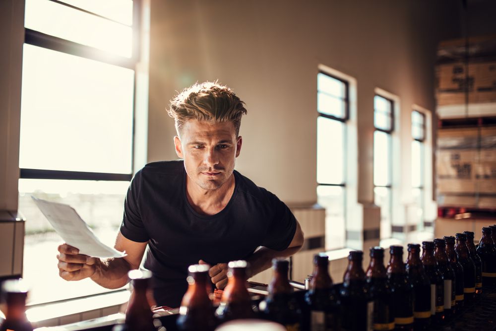 Young male inspector working in alcohol manufacturing factory checking ...