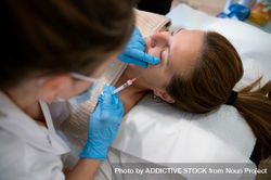 Cosmetologist administering injection in face of client during ...