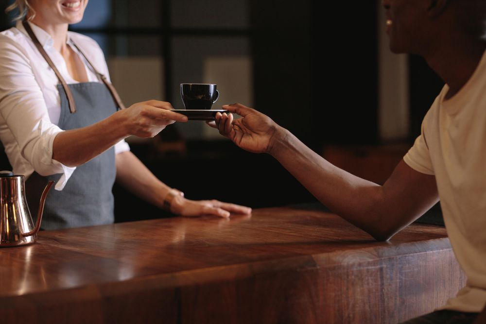 Barista handing customer a coffee over a wooden counter - Premium Photo ...