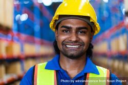 Smiling man in distribution center wearing hard hat and high visibility ...